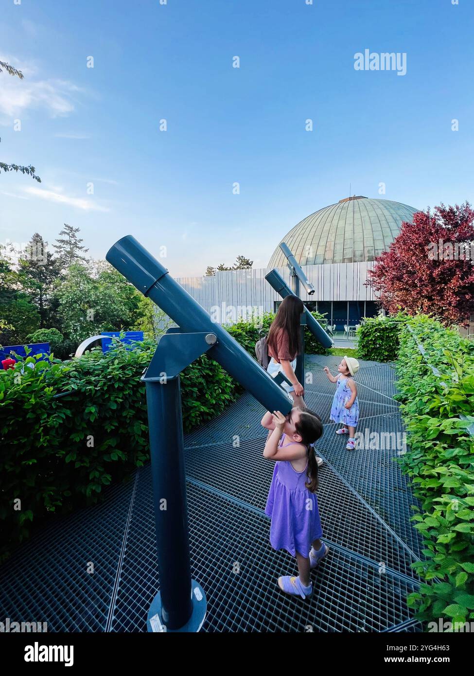Three young children enjoy a hands-on experience with telescopes at an ...
