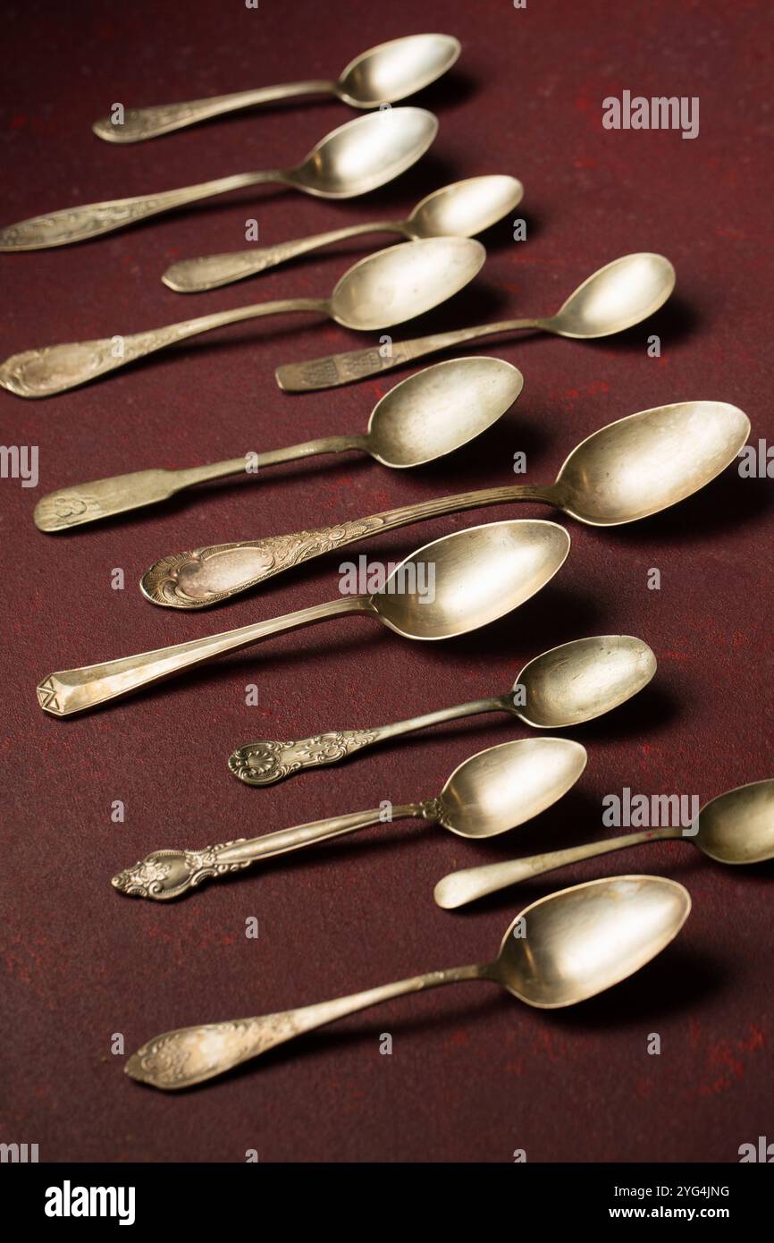 A collection of vintage spoons laid out in rows on a burgundy ...