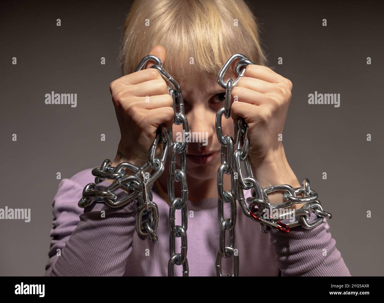 Young person holding metal chains with determined expression - Freedom ...