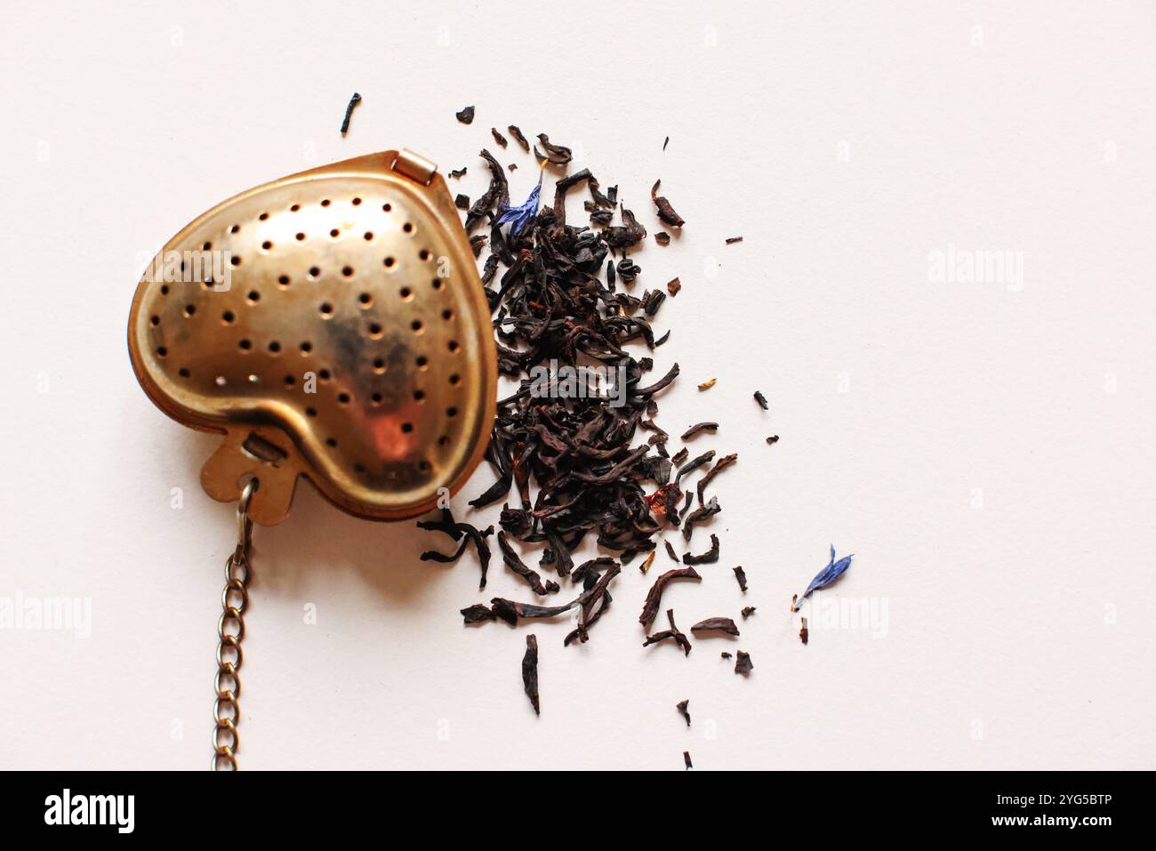 tea leaves inside of stainless steel tea bag and some of it scatter ...