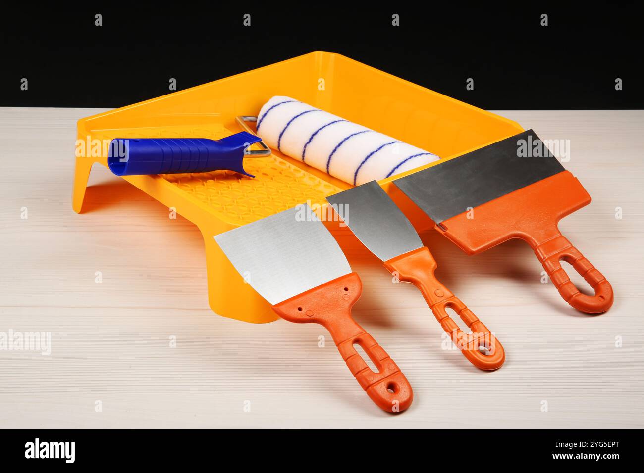 Paint roller, tray and putty knives on light wooden table. Construction tools Stock Photo - Alamy
