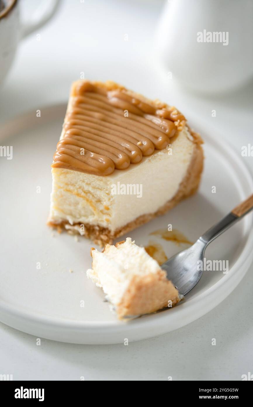 Cheesecake slice with caramel sauce topping missing a bite. Eating ...