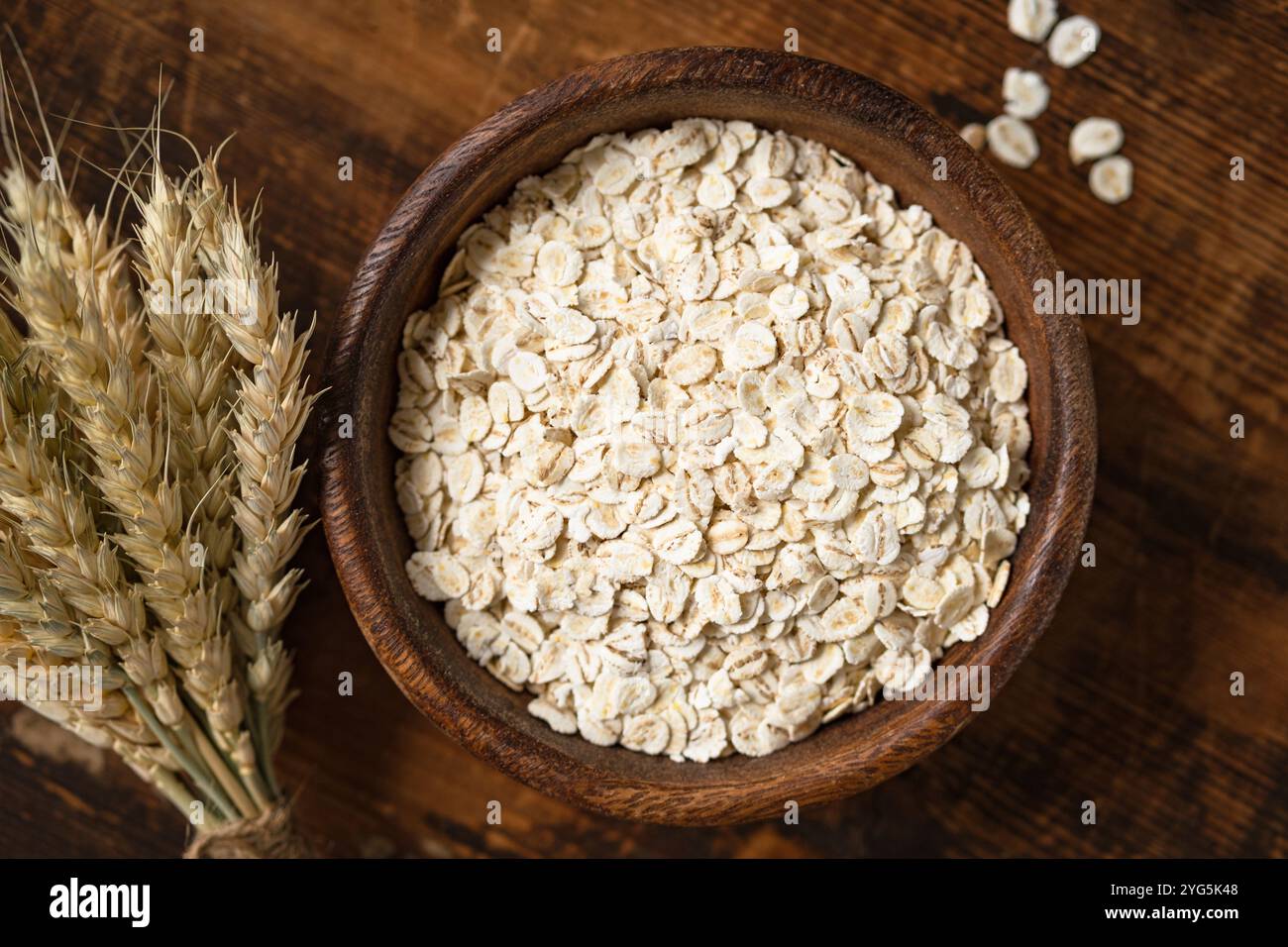 Rolled oat flakes in wooden bowl over an old wooden table background ...