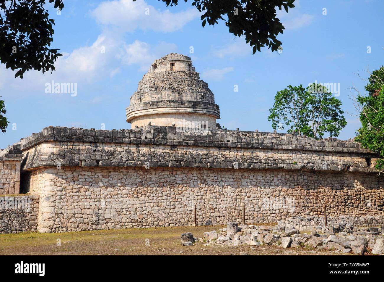 Mayan observatory at Chichen Itza with greenery and clear blue sky ...