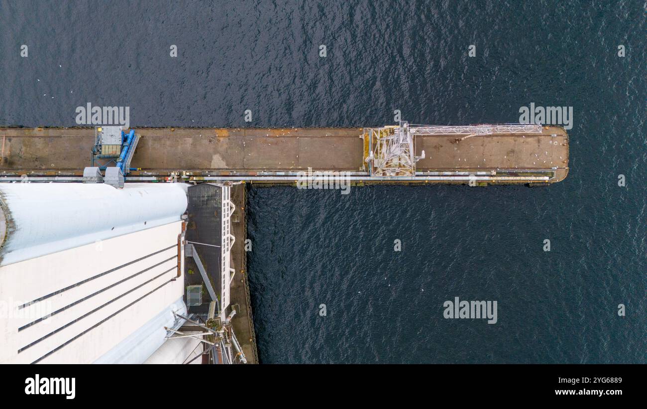 Aerial view of a long industrial pier extending into the ocean, with ...