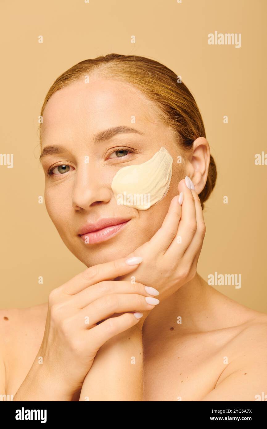 A young beautiful woman smiles while applying a soothing mask to her ...