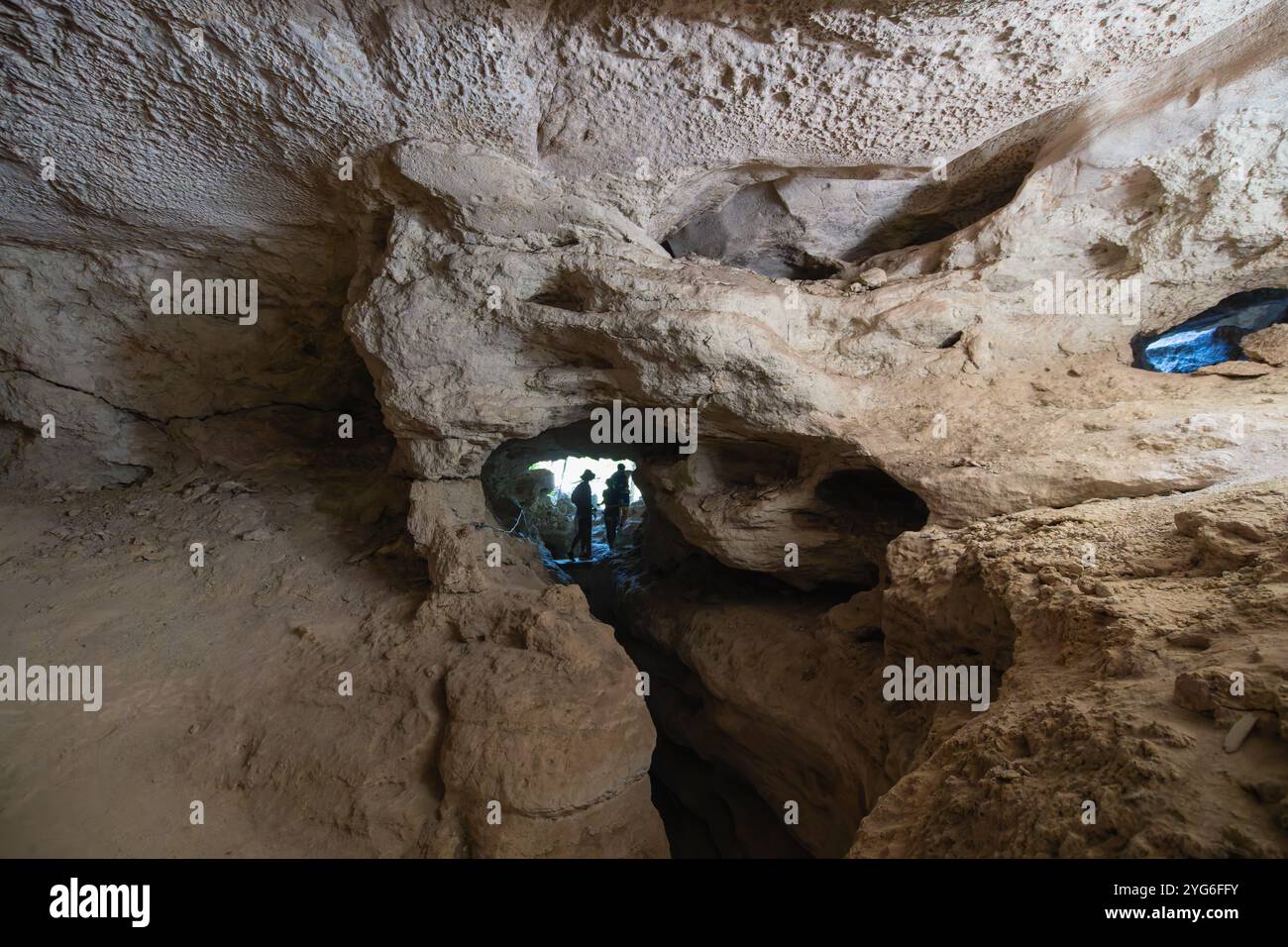 Tourists navigate through narrow limestone caves with a deep ravine ...