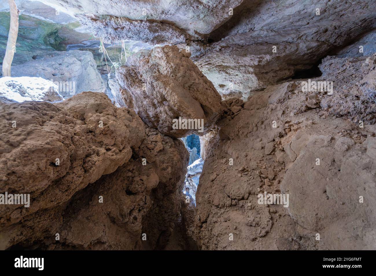 Tourists navigate through narrow limestone caves with a deep ravine ...