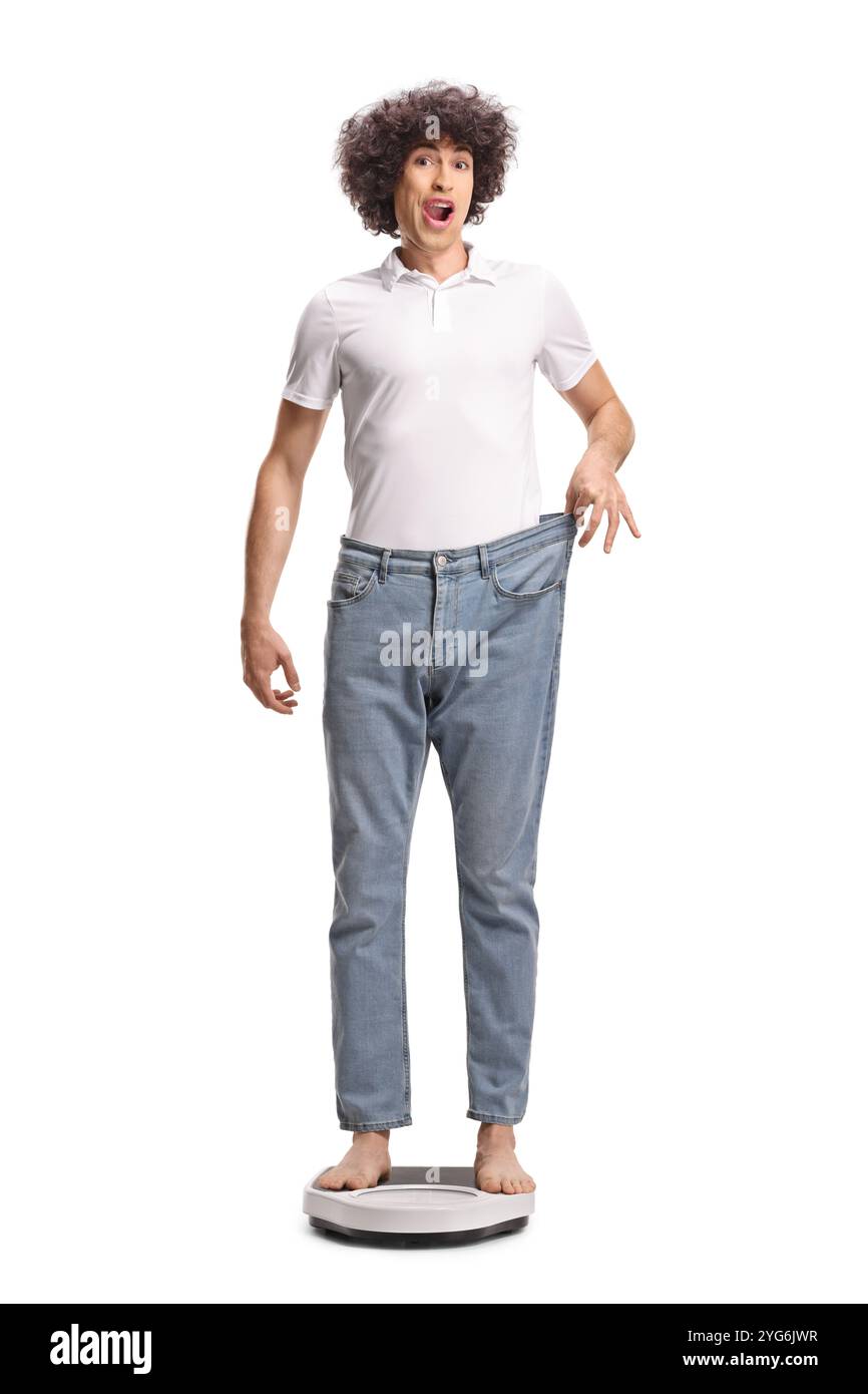 Young man on a weight scale wearing a big sized jeans isolated on white ...