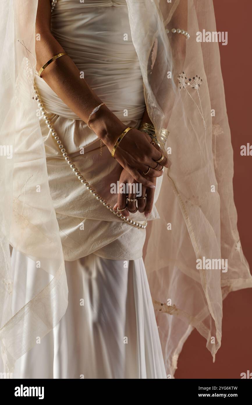 Draped in a white dress and elegant pearls, a beautiful woman radiates ...