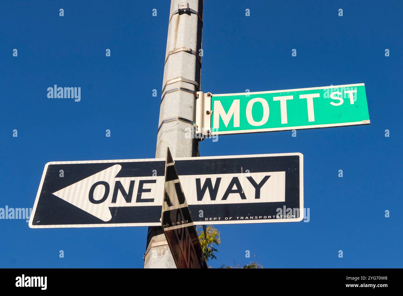 Street signs at Mott Street and a one-way arrow against a clear blue ...