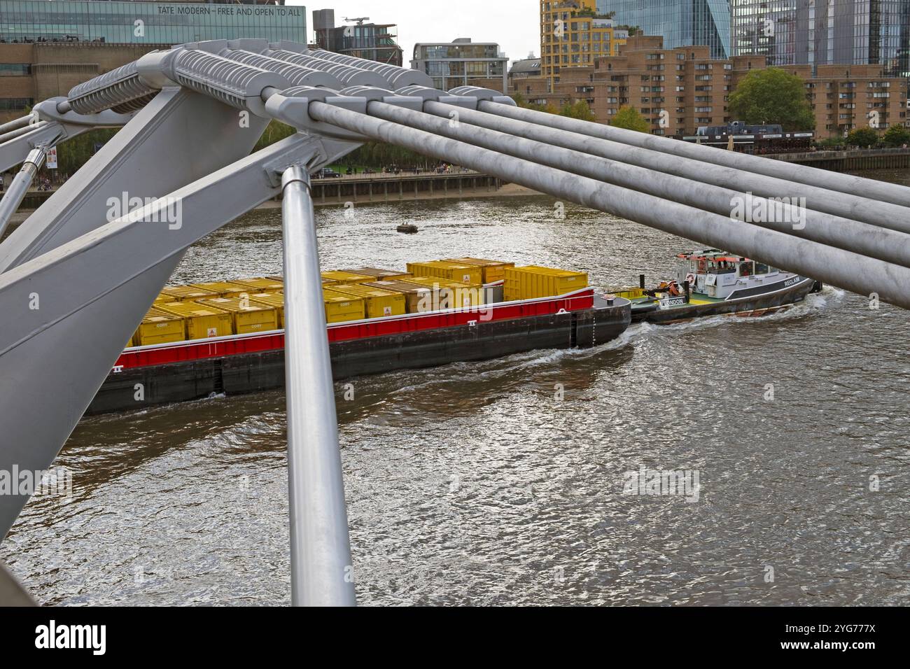 View of tugboat pulling barge with yellow containers under the ...