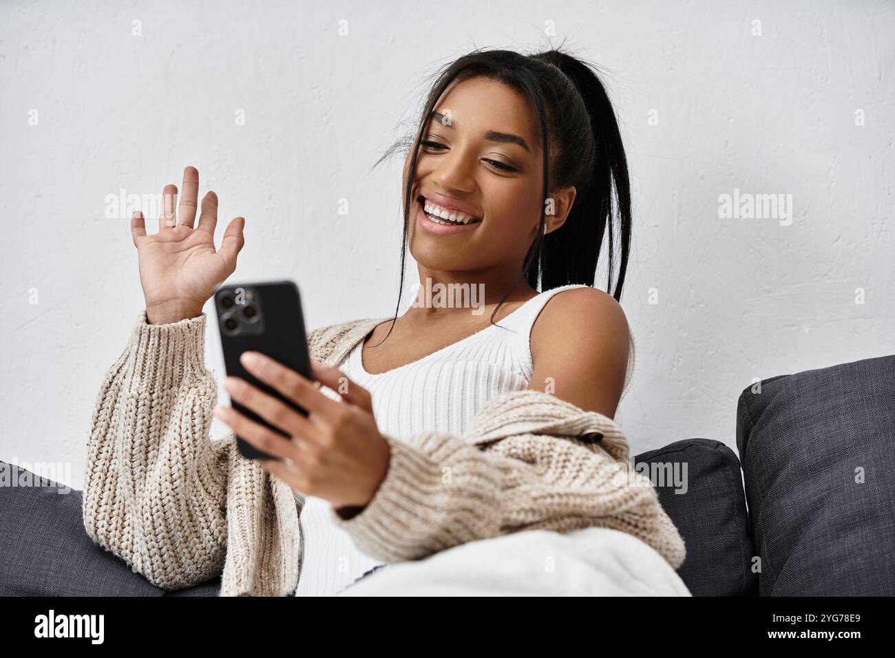 A cheerful young woman engages in remote learning at home, smiling as ...