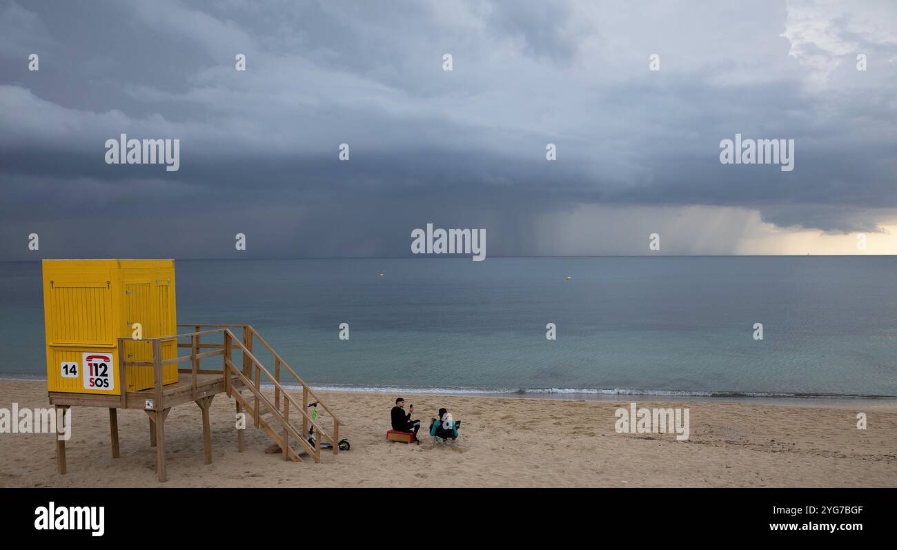 06 November 2024, Spain, Palma: People sit on the beach of Can Pere ...