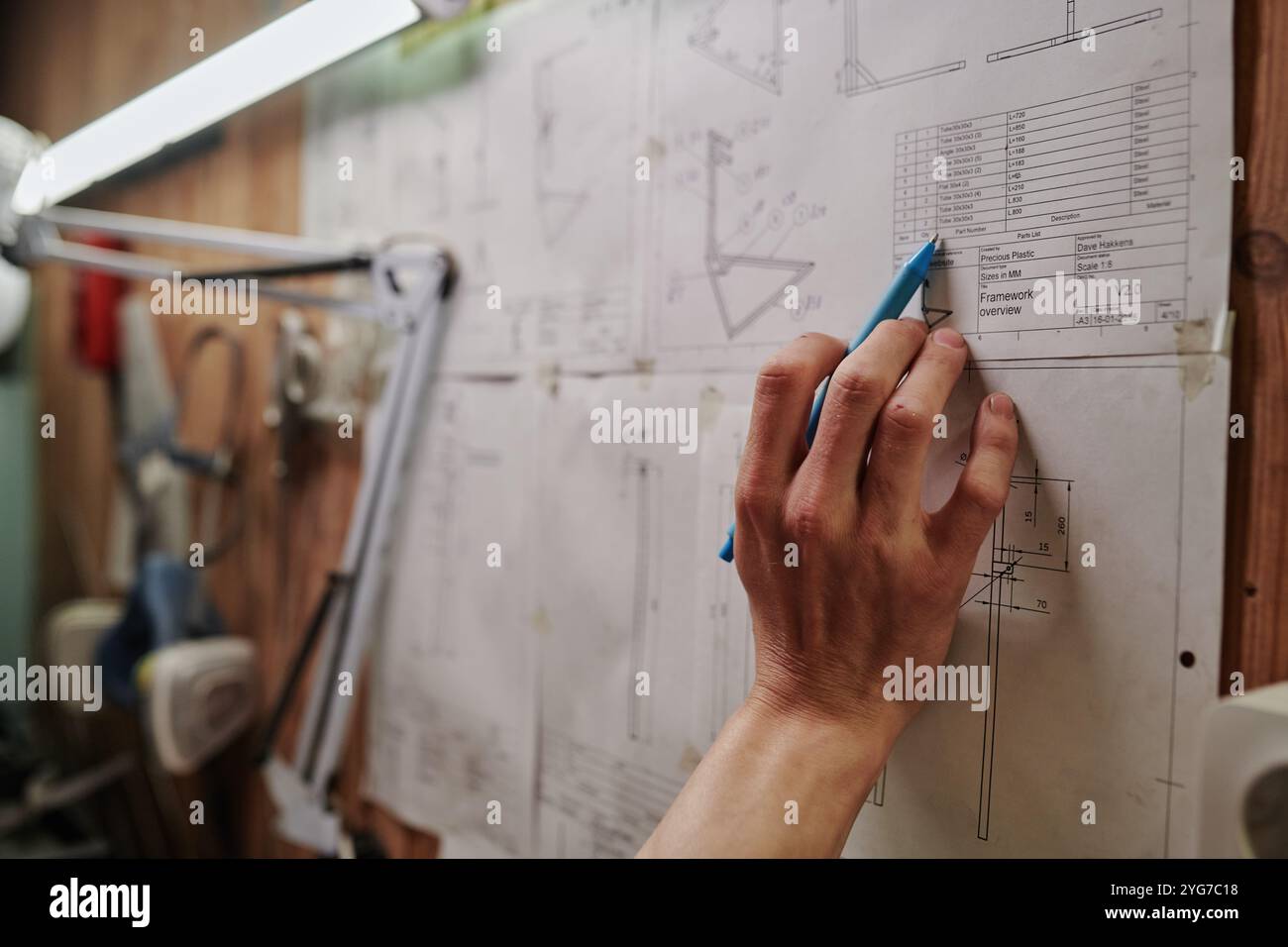 Hand of young unrecognizable male engineer with pen pointing at number ...