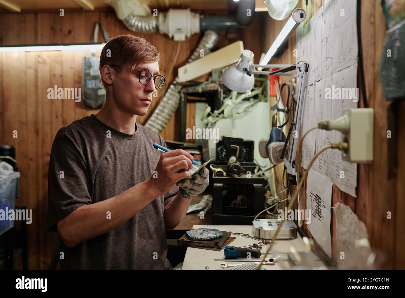 Young technician taking notes in notepad while standing in front of ...