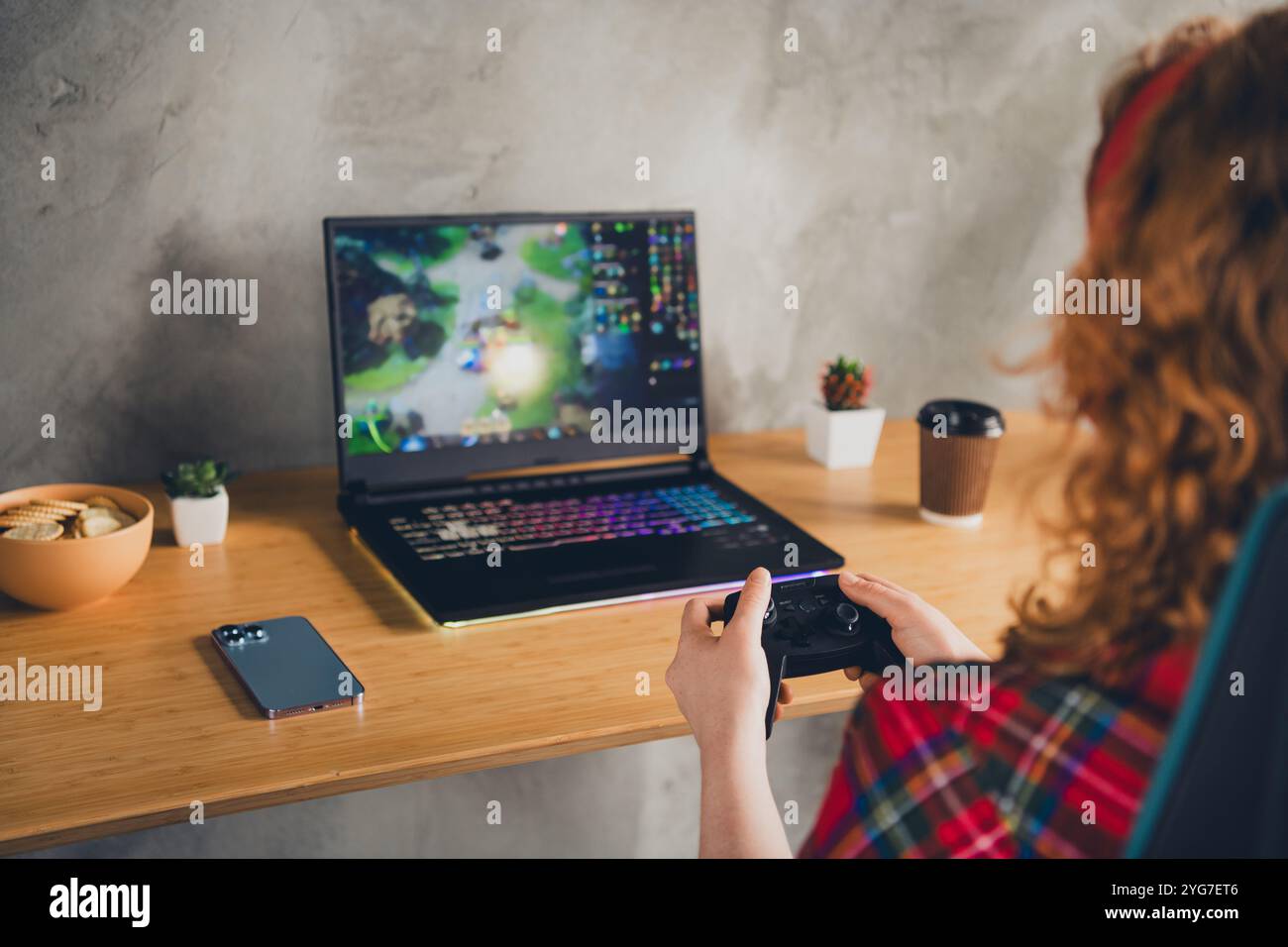 Woman playing video game on laptop at cozy home desk Stock Photo - Alamy
