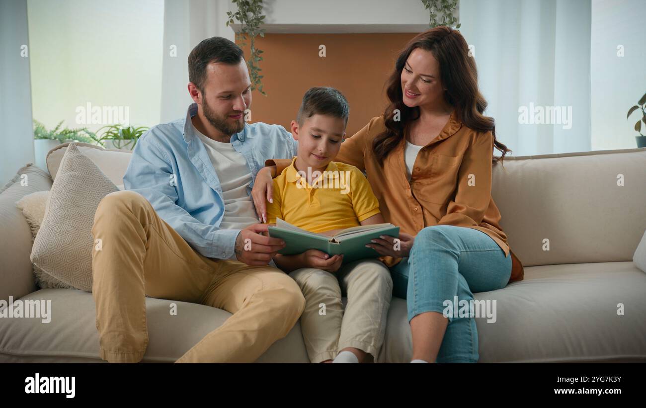 Happy caucasian family dad mom son reading fairytale story book on sofa in cozy living room ...