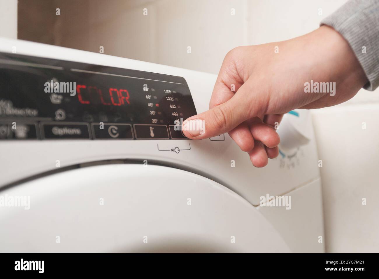 A person presses a button to select the spin cycle of the washing ...