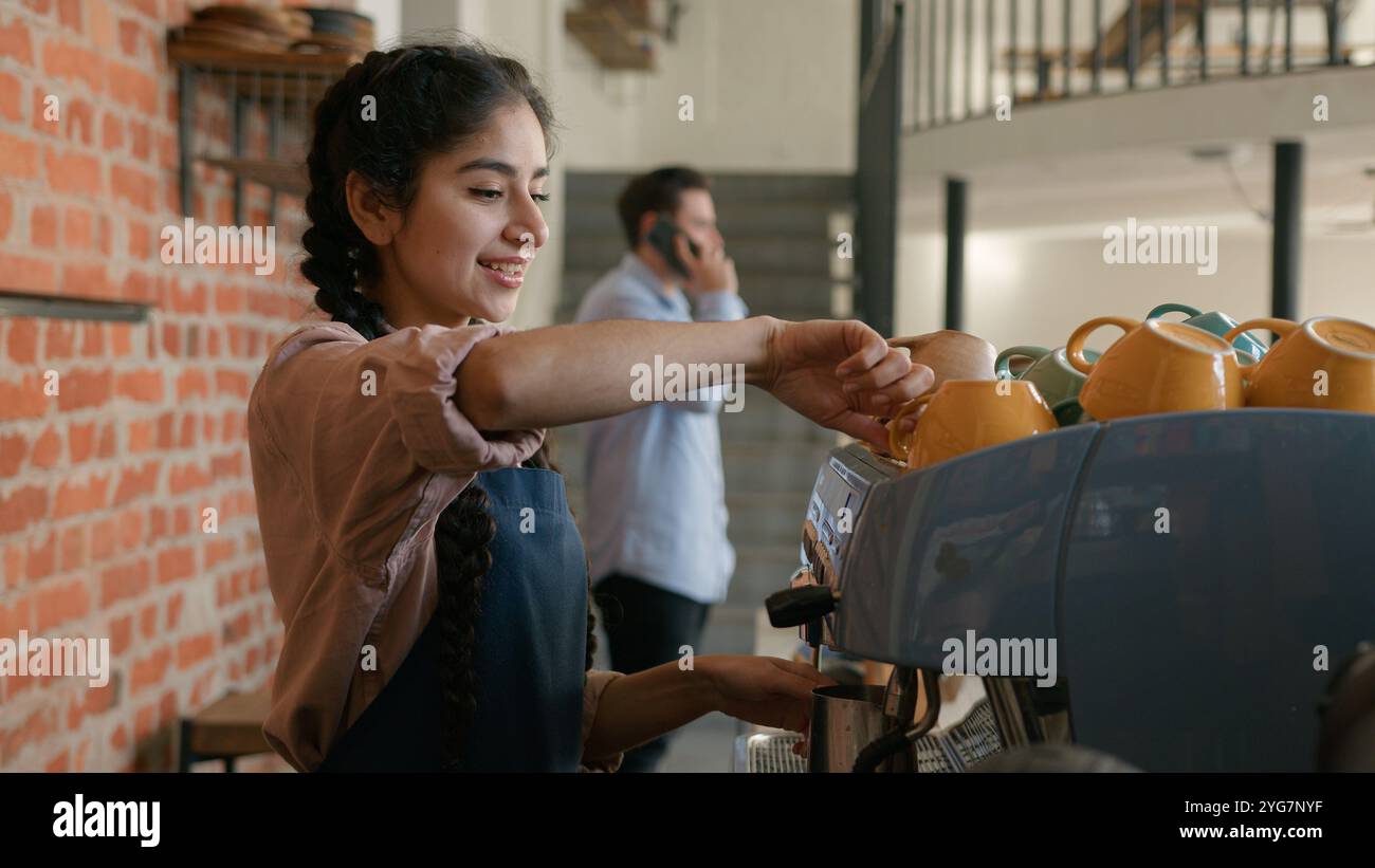 Indian woman waitress barista in apron wipe dust using cleaning duster ...