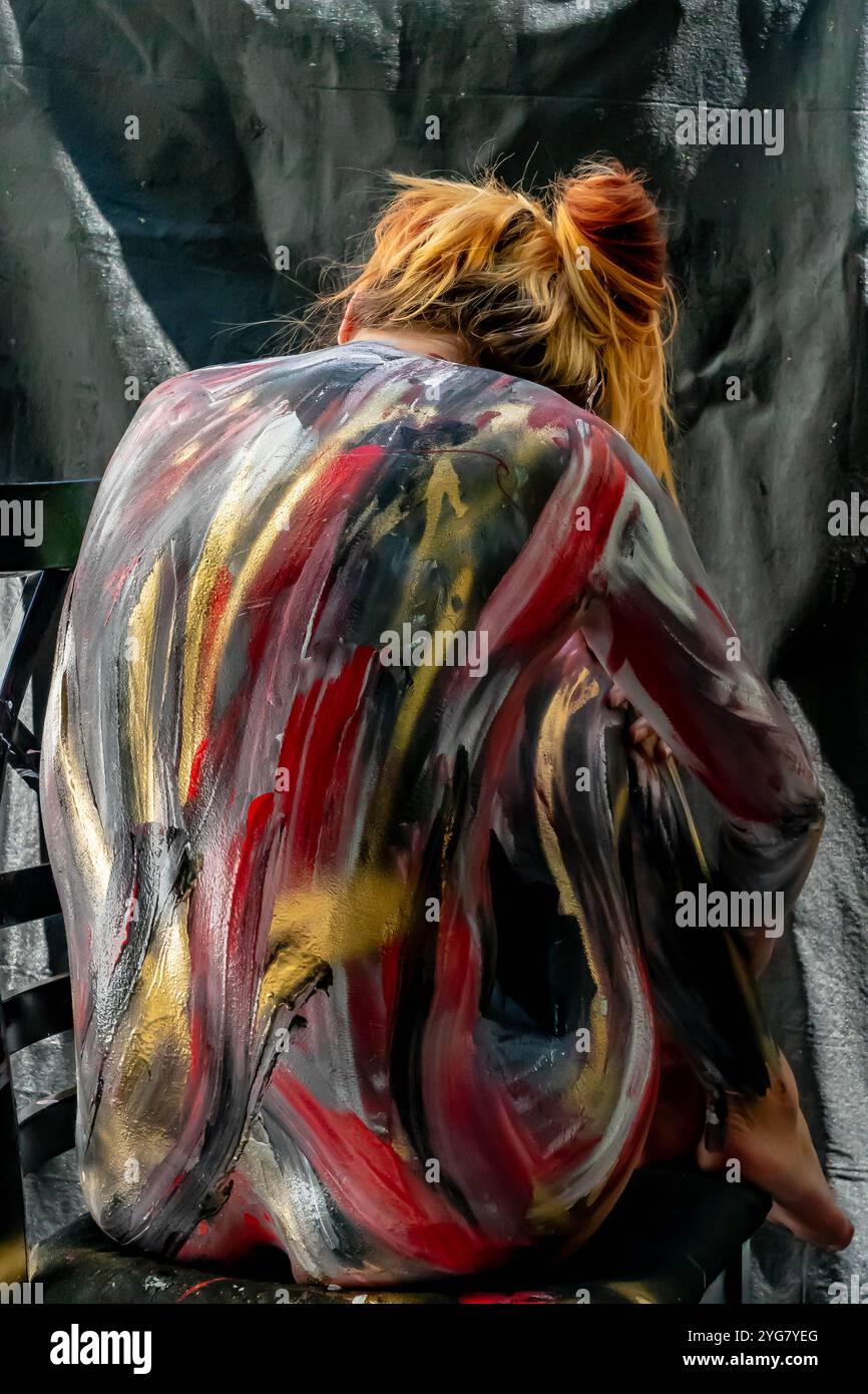 A model poses gracefully, her body adorned in vibrant body paint, with brilliant, sweeping ...