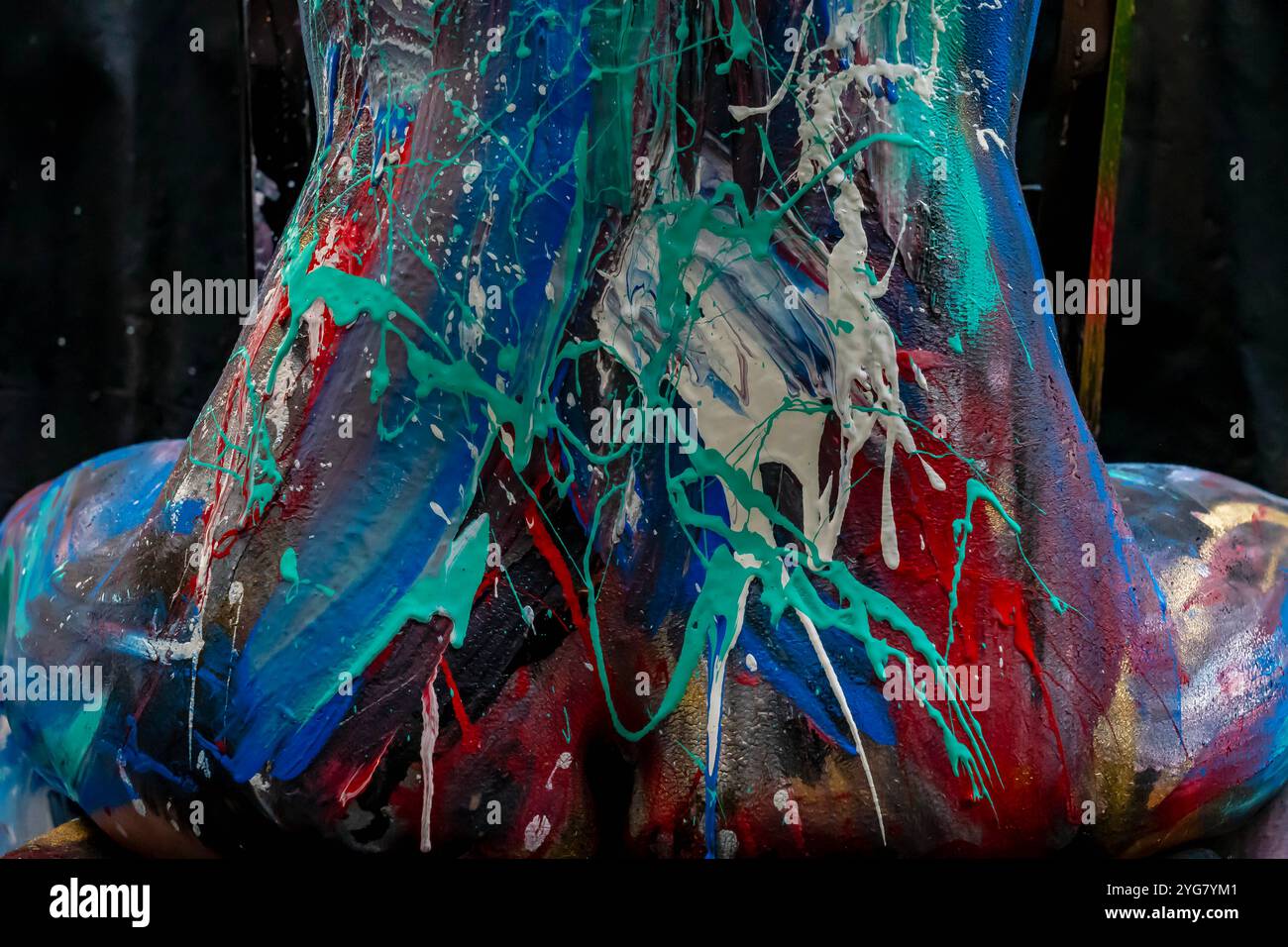 A model poses gracefully, her body adorned in vibrant body paint, with brilliant, sweeping ...