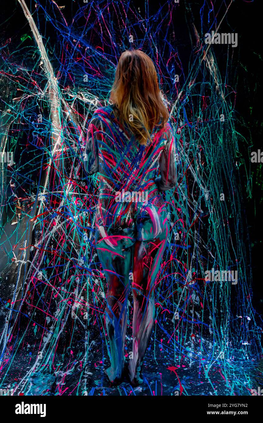 A model poses gracefully, her body adorned in vibrant body paint, with ...