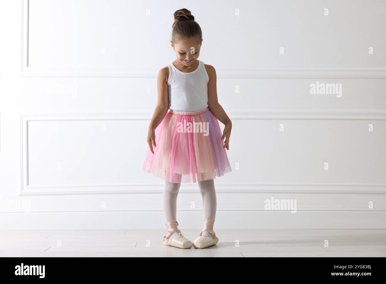 Little ballerina practicing dance moves near white wall indoors Stock ...