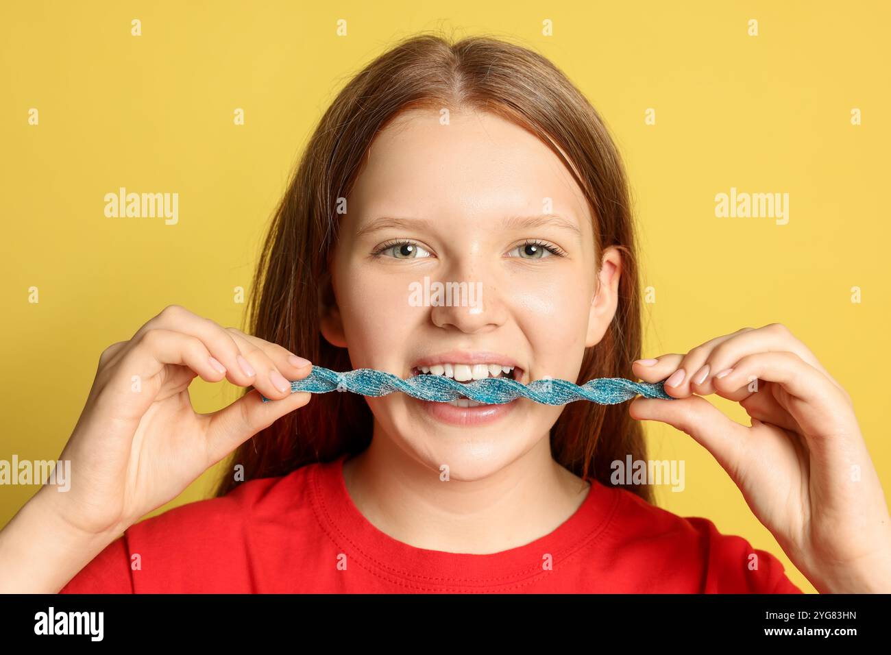 Teenage girl eating tasty gummy candy on yellow background Stock Photo ...