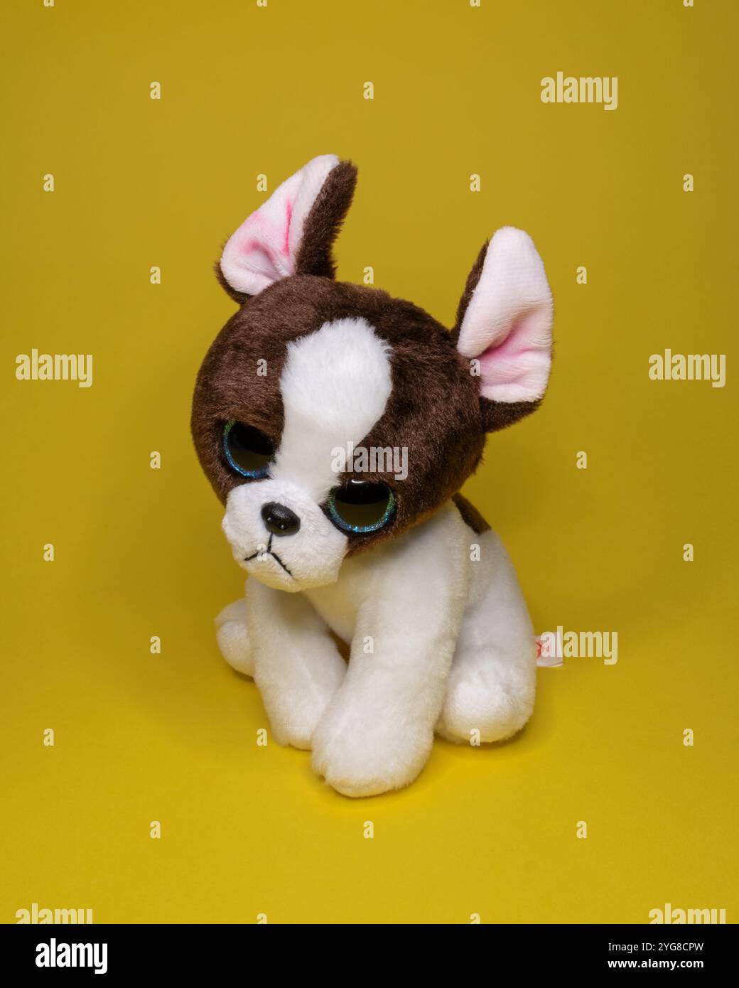 Sad little puppy mascot toy on a yellow background, homeless animals ...