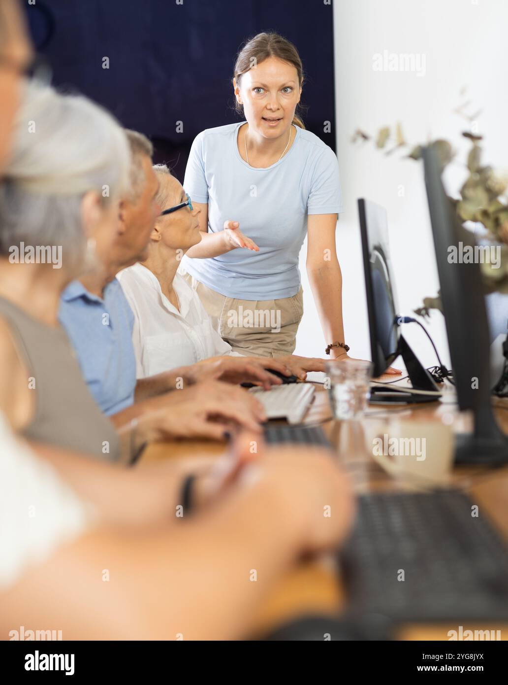 Woman teacher teaching elderly people how to use computer Stock Photo ...