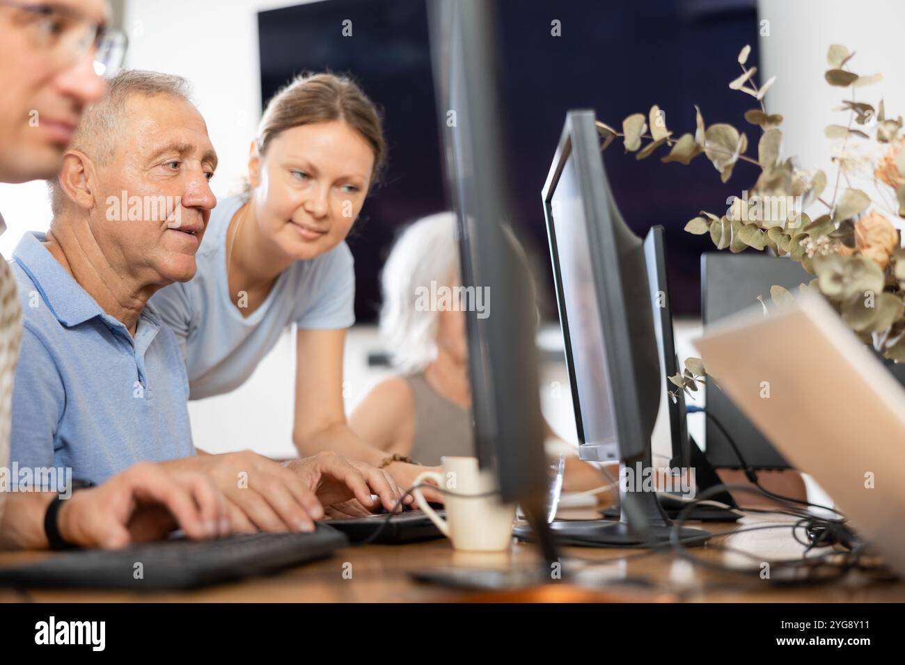 Old man learning computer programs with teacher in training room Stock ...
