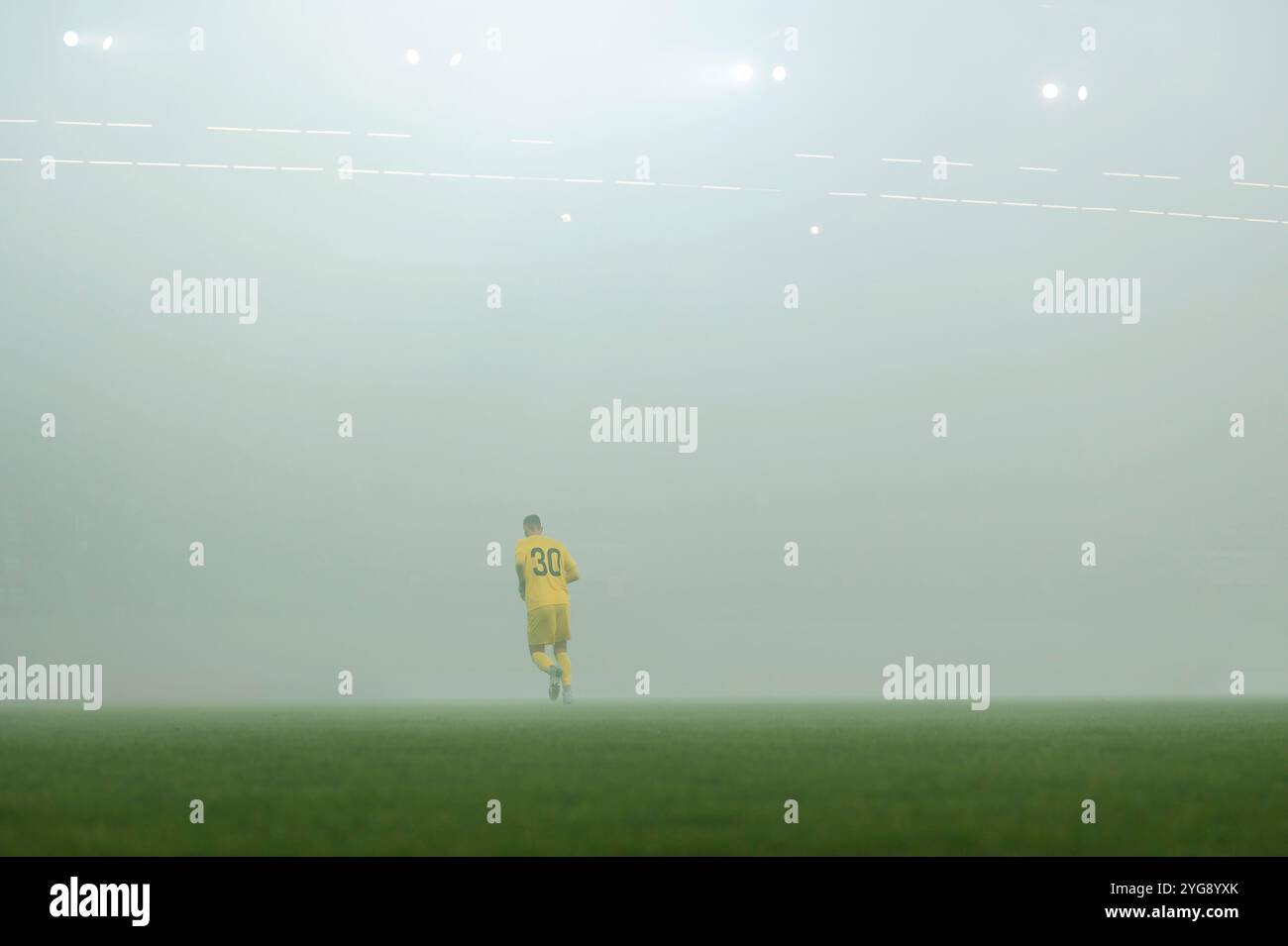 Footballer on the field during fog at the stadium Stock Photo - Alamy