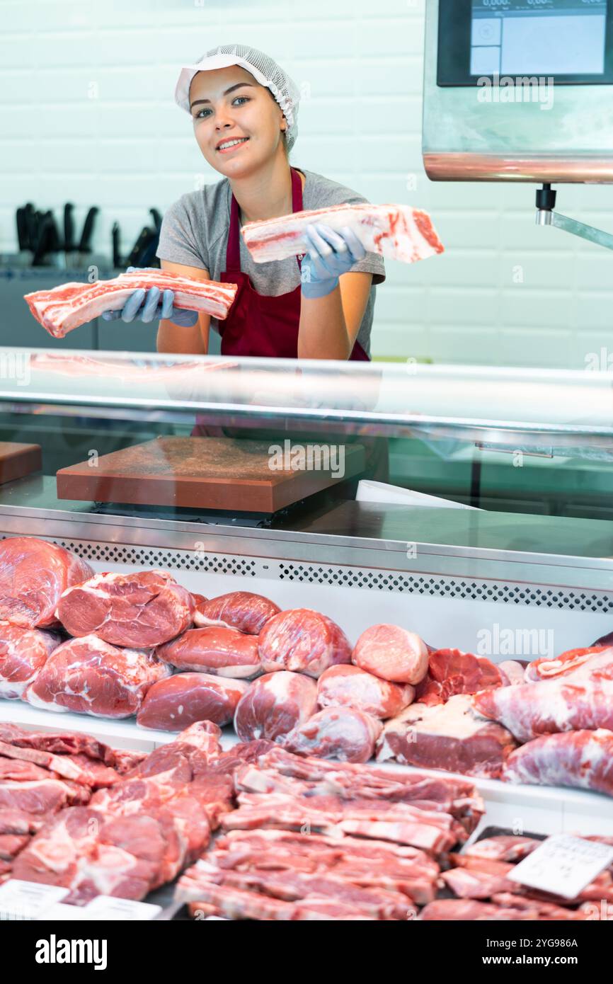 Young woman seller laying out beef ribs in butcher shop Stock Photo - Alamy