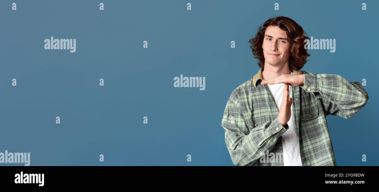 Expressing refusal. Handsome teenager gesturing TIME OUT on turquoise ...