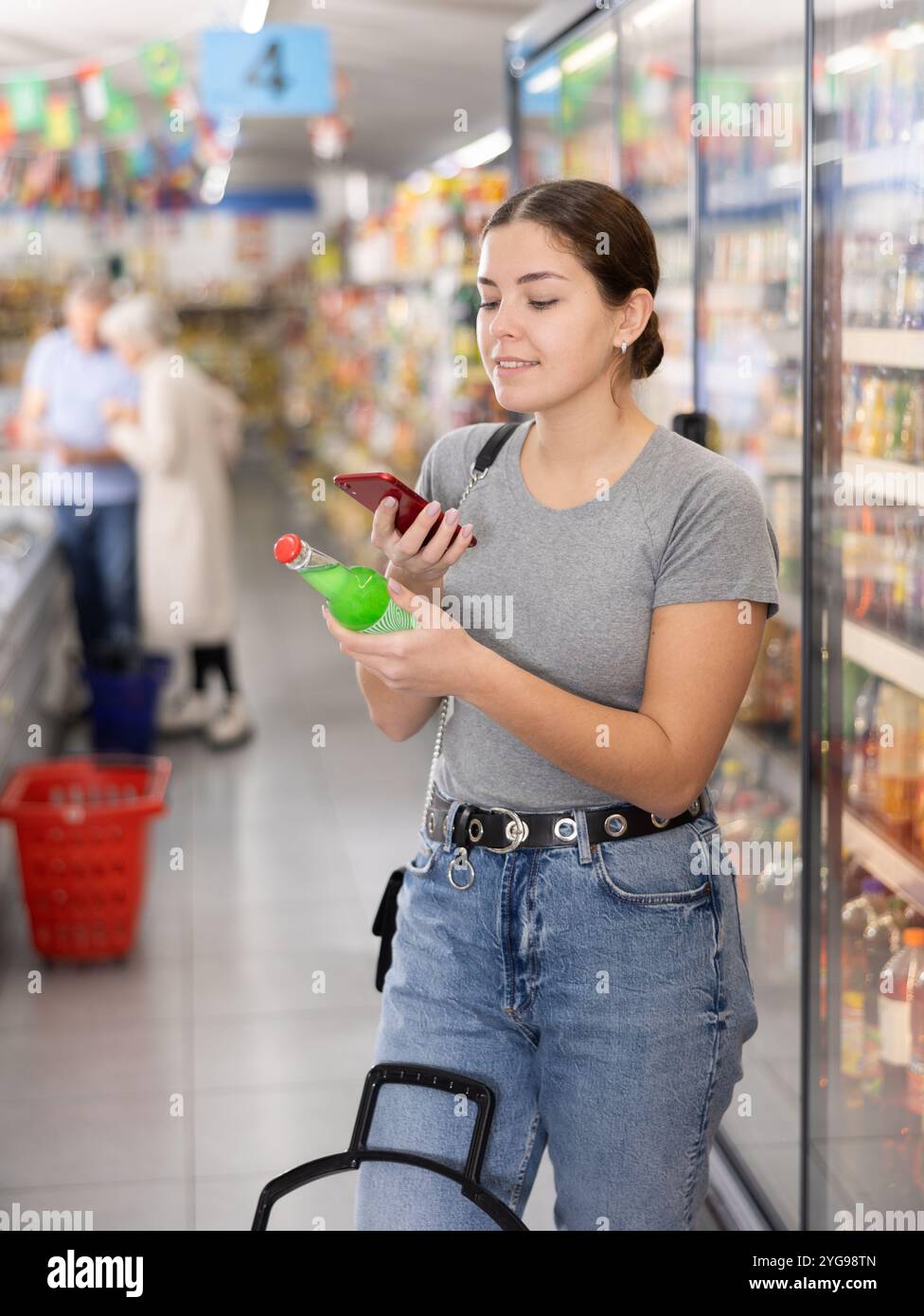 Young girl scanning barcode on bottle of soft drink in supermarket ...