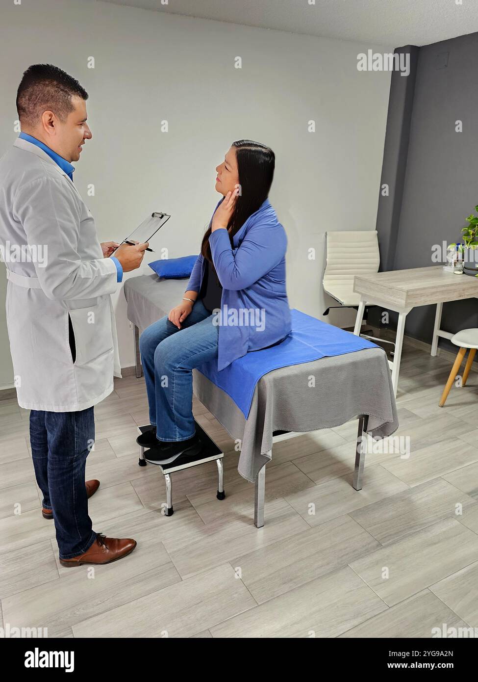 Dark-haired male doctor does a medical checkup checks the throat of ...