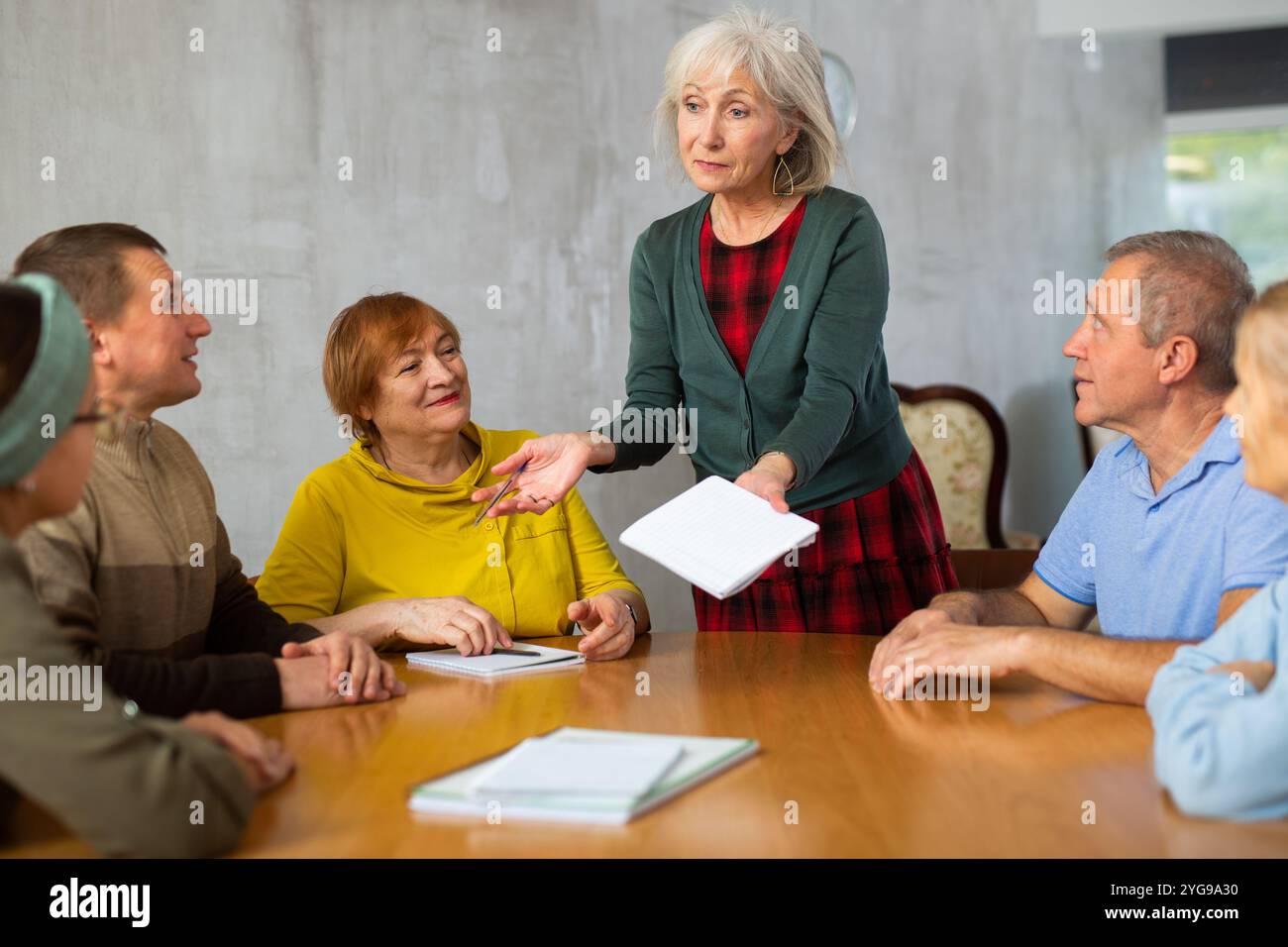 Elderly people communicating in language club with female tutor Stock ...