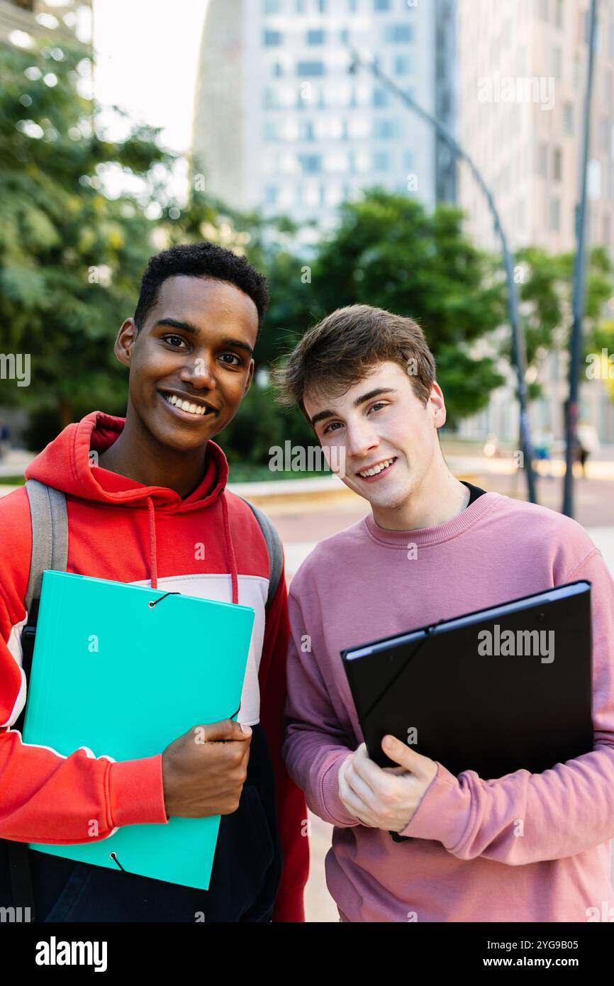Two young university male students smiling together at camera on campus ...
