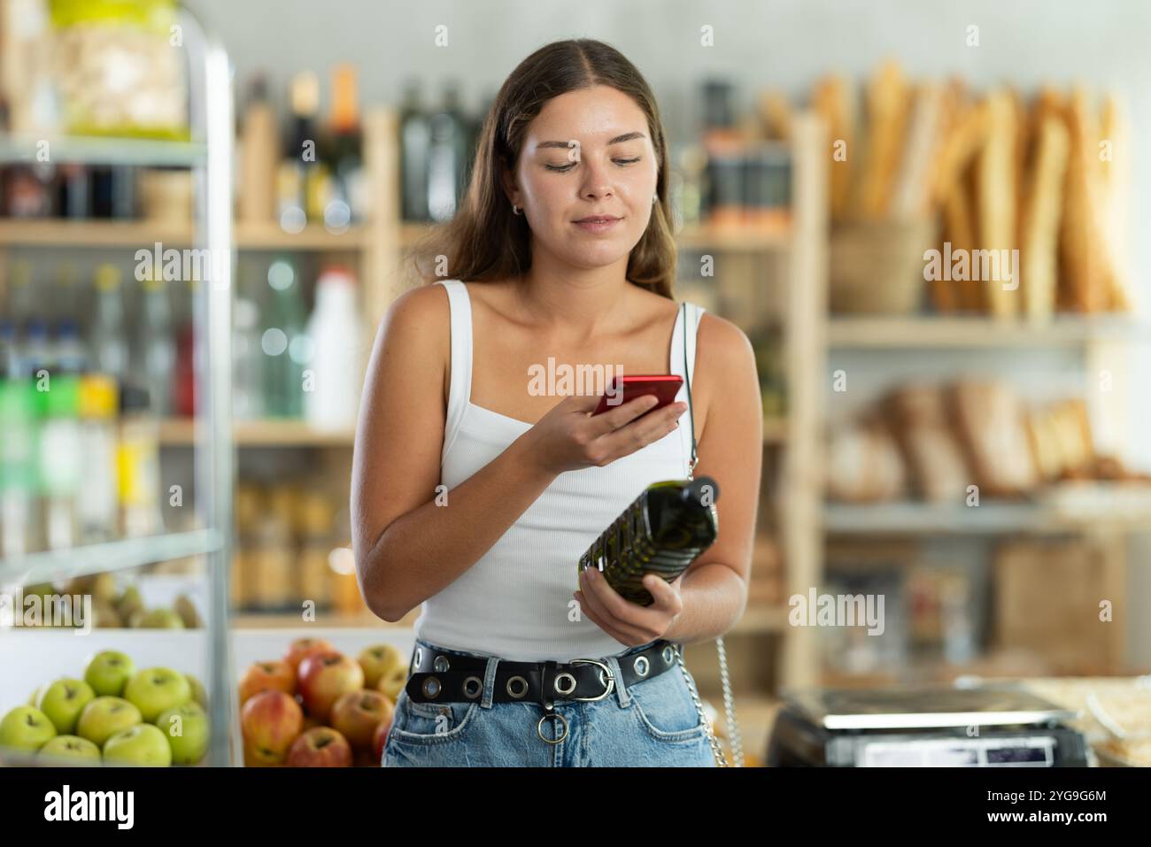 Checking expiration date of olive oil - female buyer scans QR code on ...