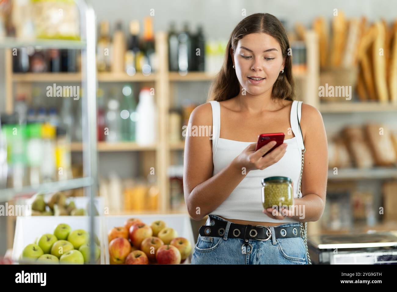 Female shopper scans QR code on green peas jar label using smartphone ...