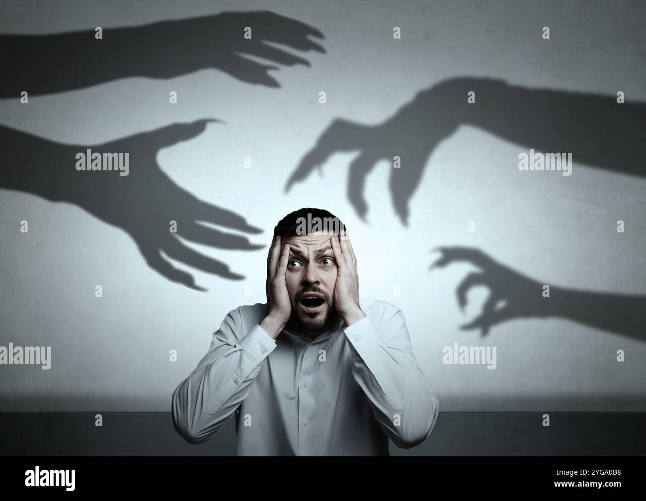 Man scared by monstrous hands reaching for him. Creepy shadows on grey ...