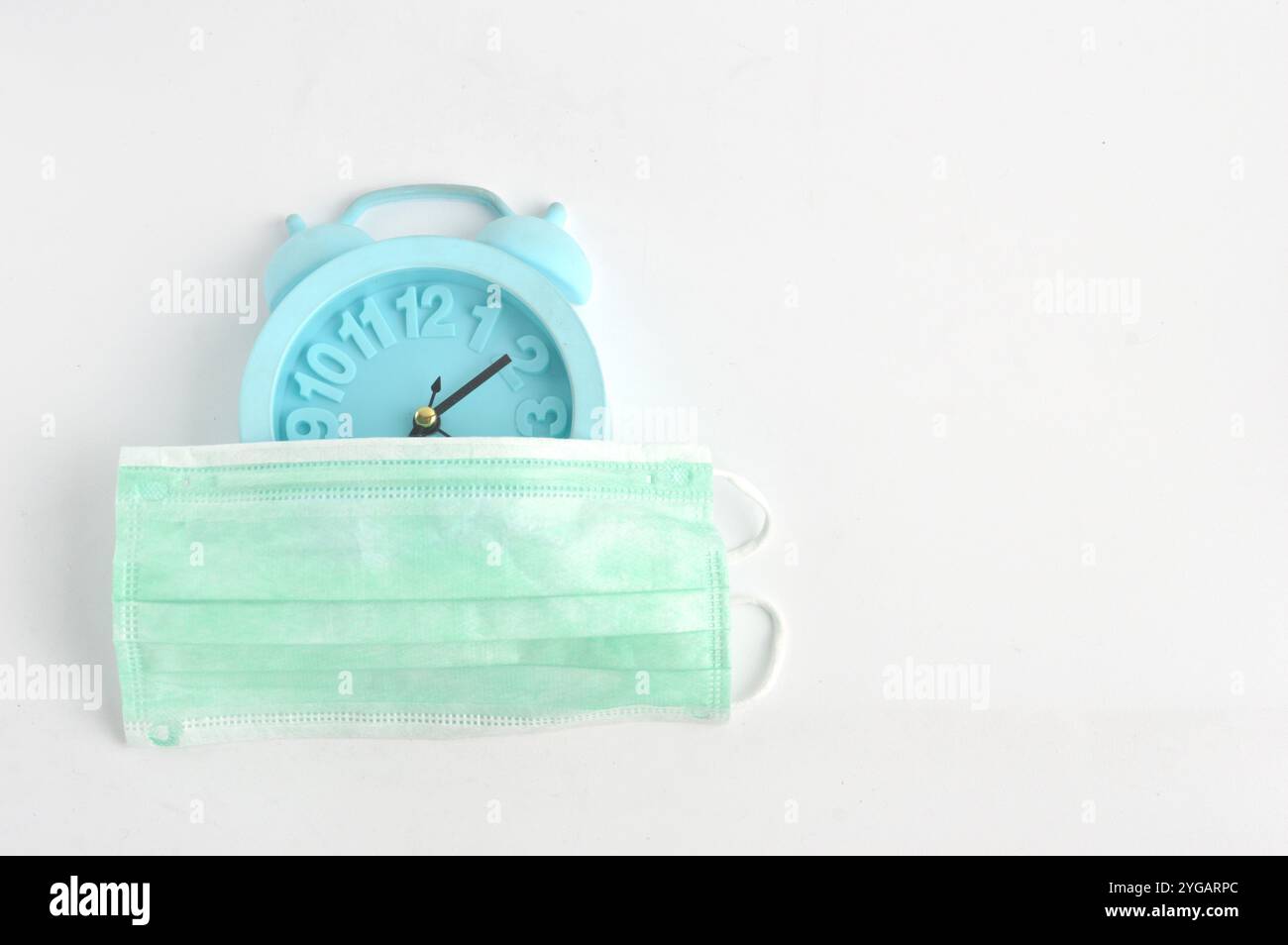 surgical mask covering the alarm clock isolated on white background ...