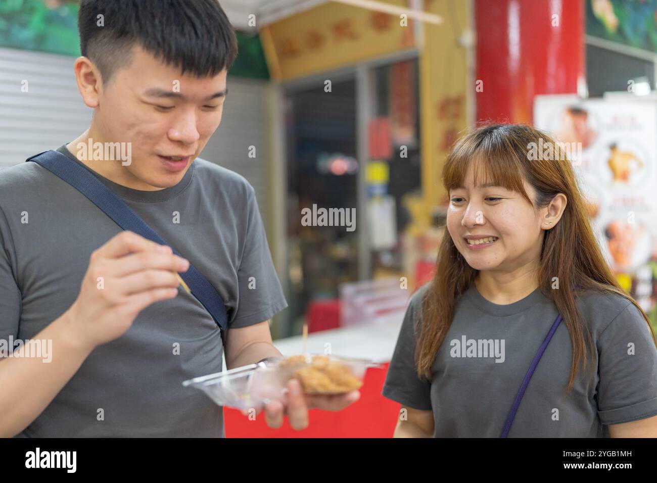 Chinese Malaysian couple in their 30s buying and eating kinako mochi ...