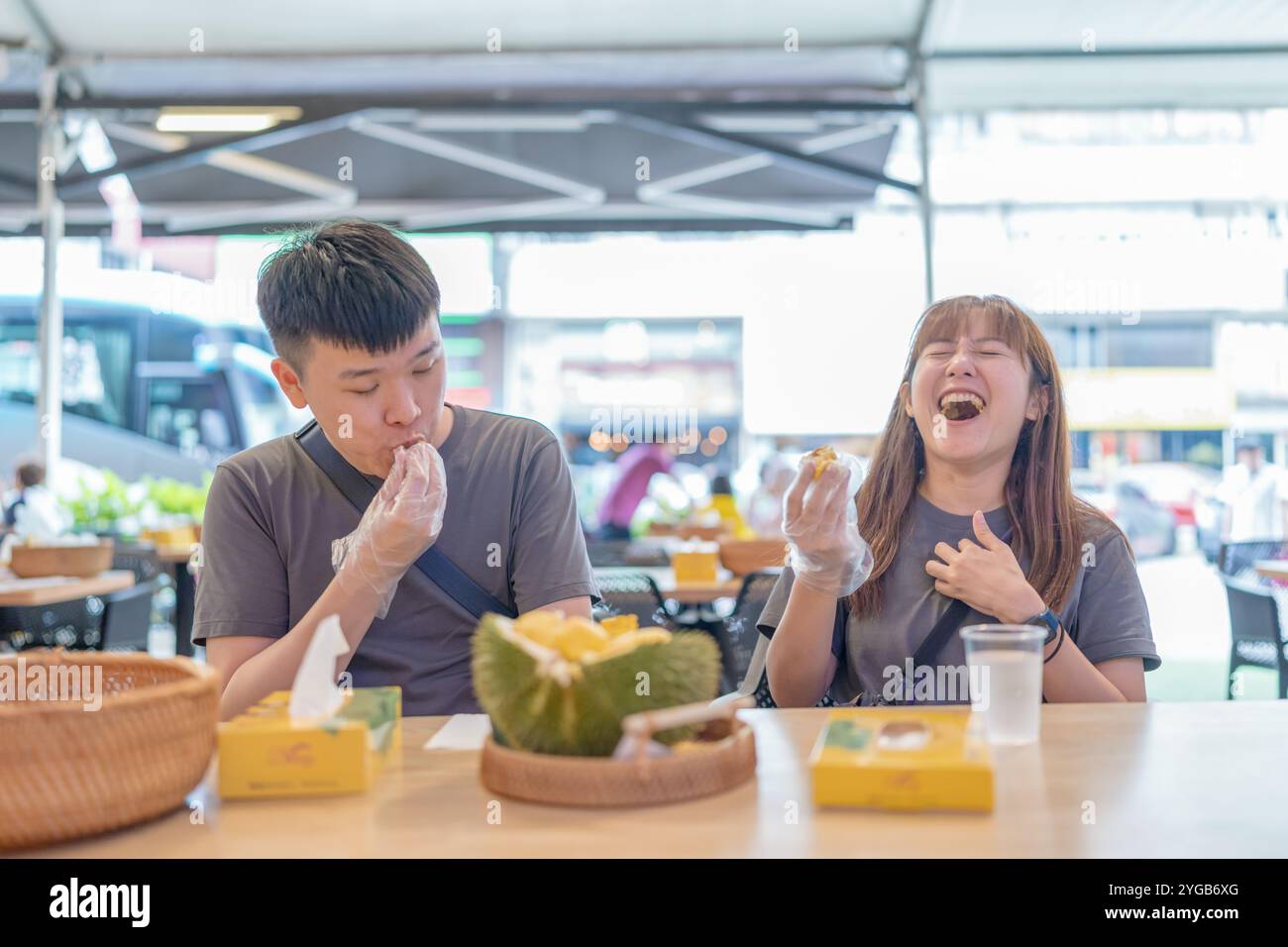 June 2024. A Chinese-Malaysian couple in their 30s chat while eating ...