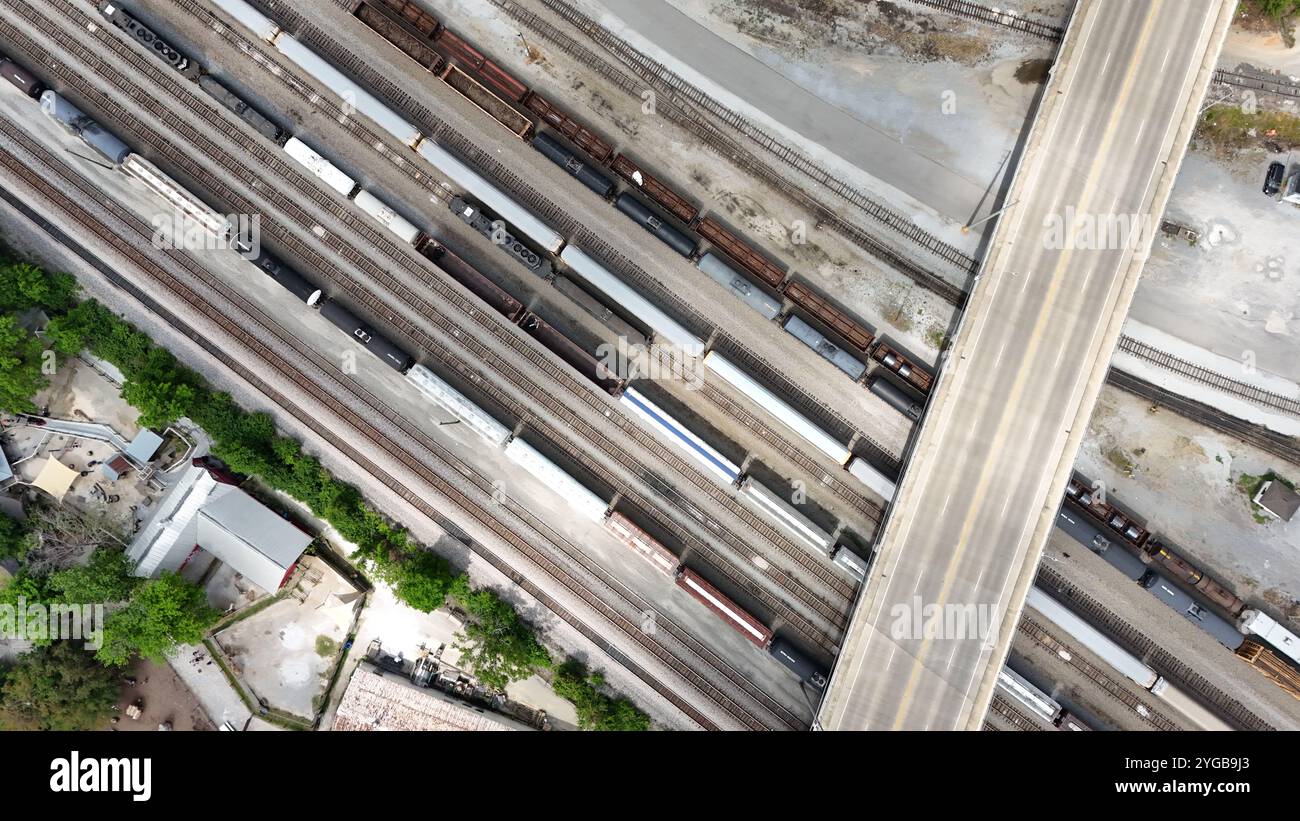 An overhead drone shot captures the railroad tracks as a train passes through, showcasing the ...