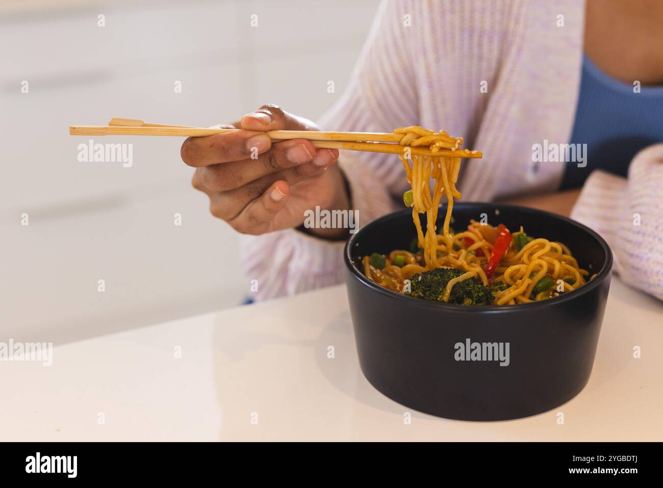 Using chopsticks, asian woman enjoying delicious noodles with ...
