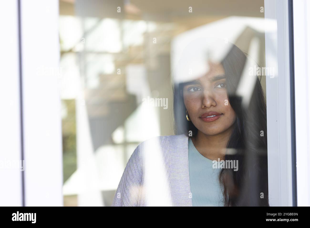 Asian woman gazing thoughtfully through window, reflecting on holiday ...
