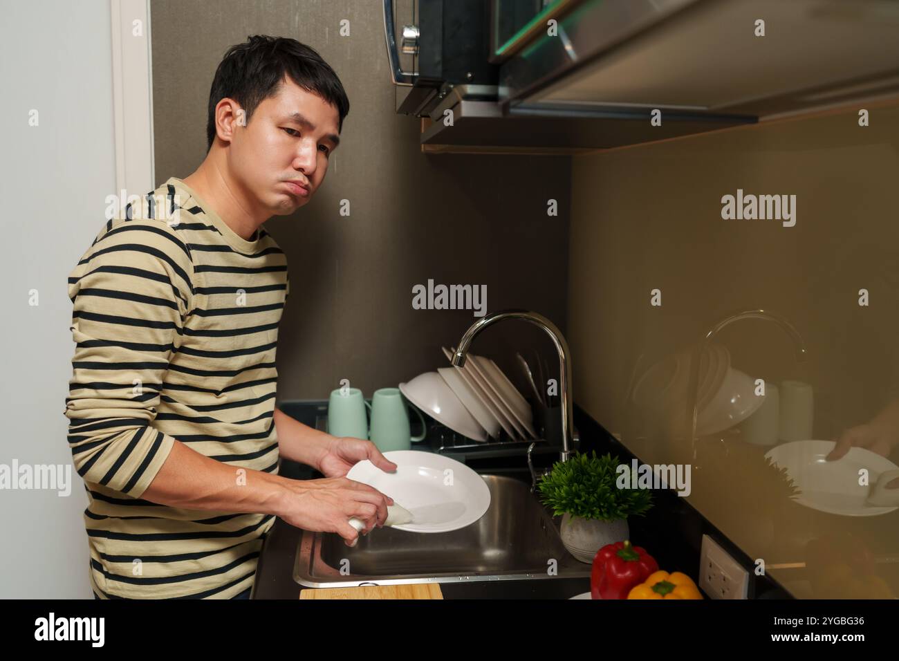 tired man washing dishes in the sink in the kitchen at home Stock Photo ...