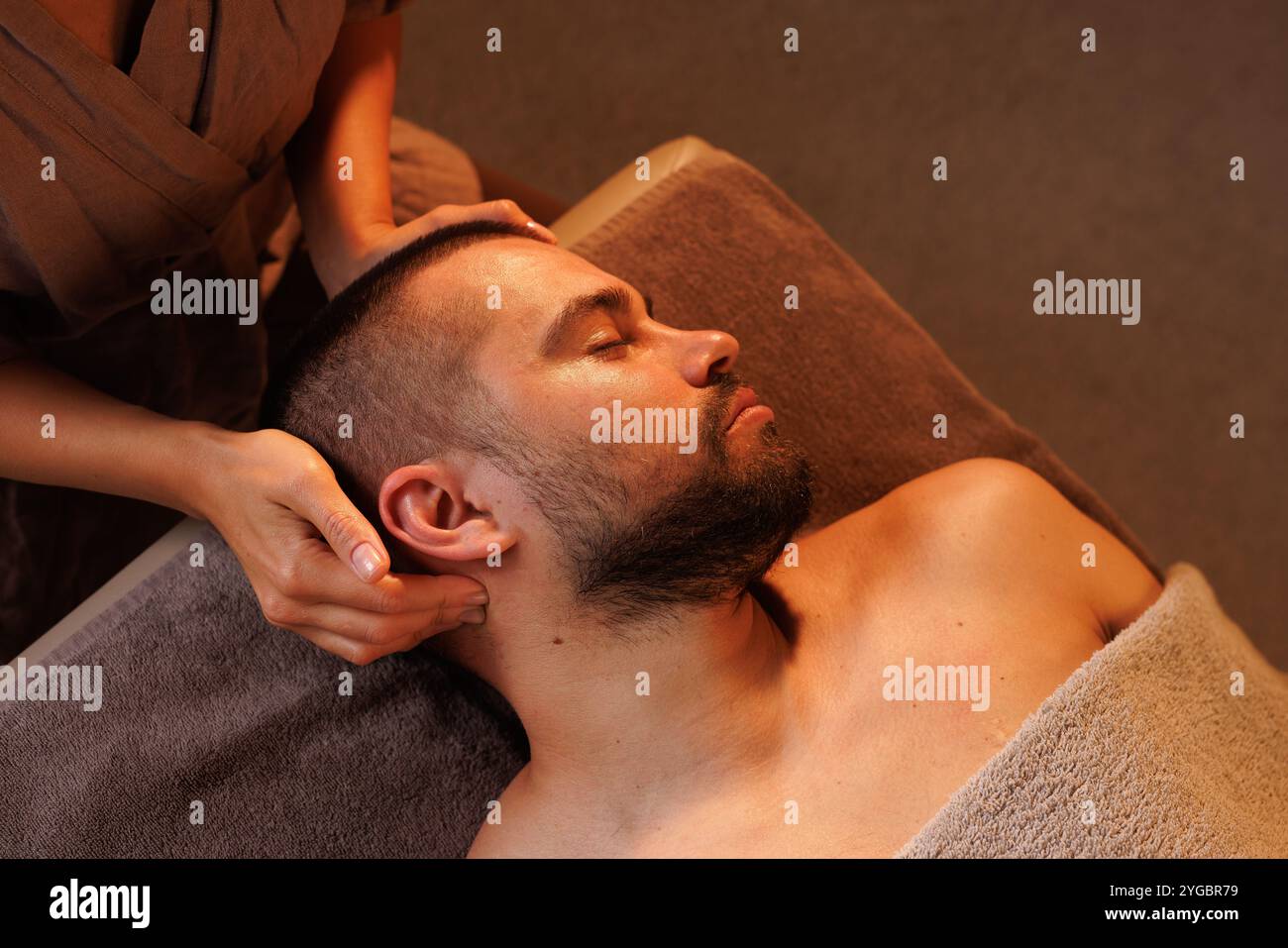 girl massage therapist gives head massage to man in office with warm light, pain in head and ...